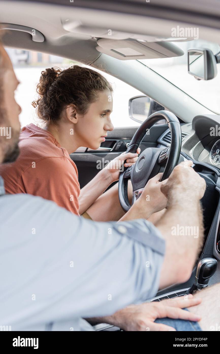 bearded father pointing at speedometer while teaching teenage son how ...