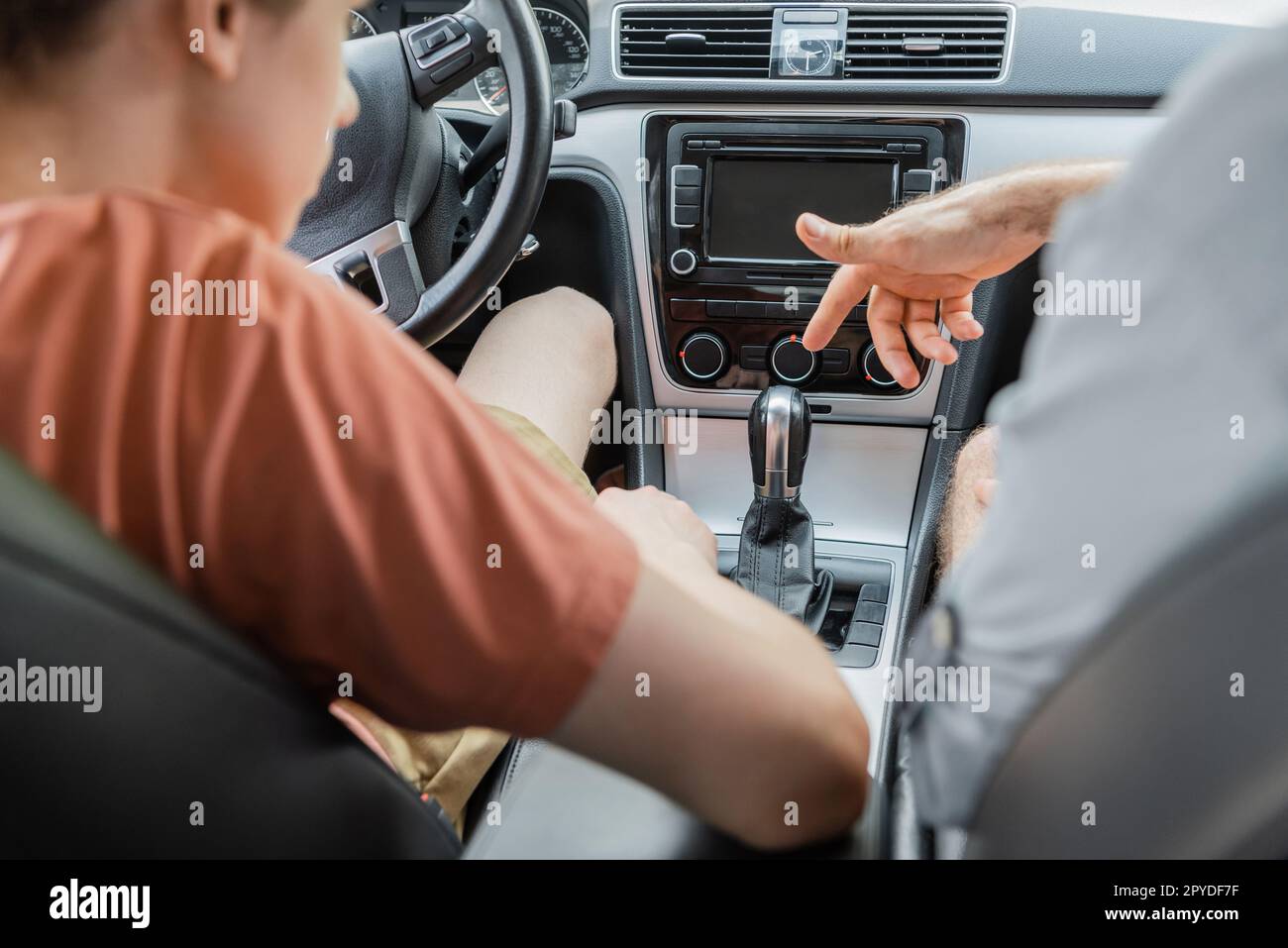 father pointing at changing gear handle while teaching son how to drive ...