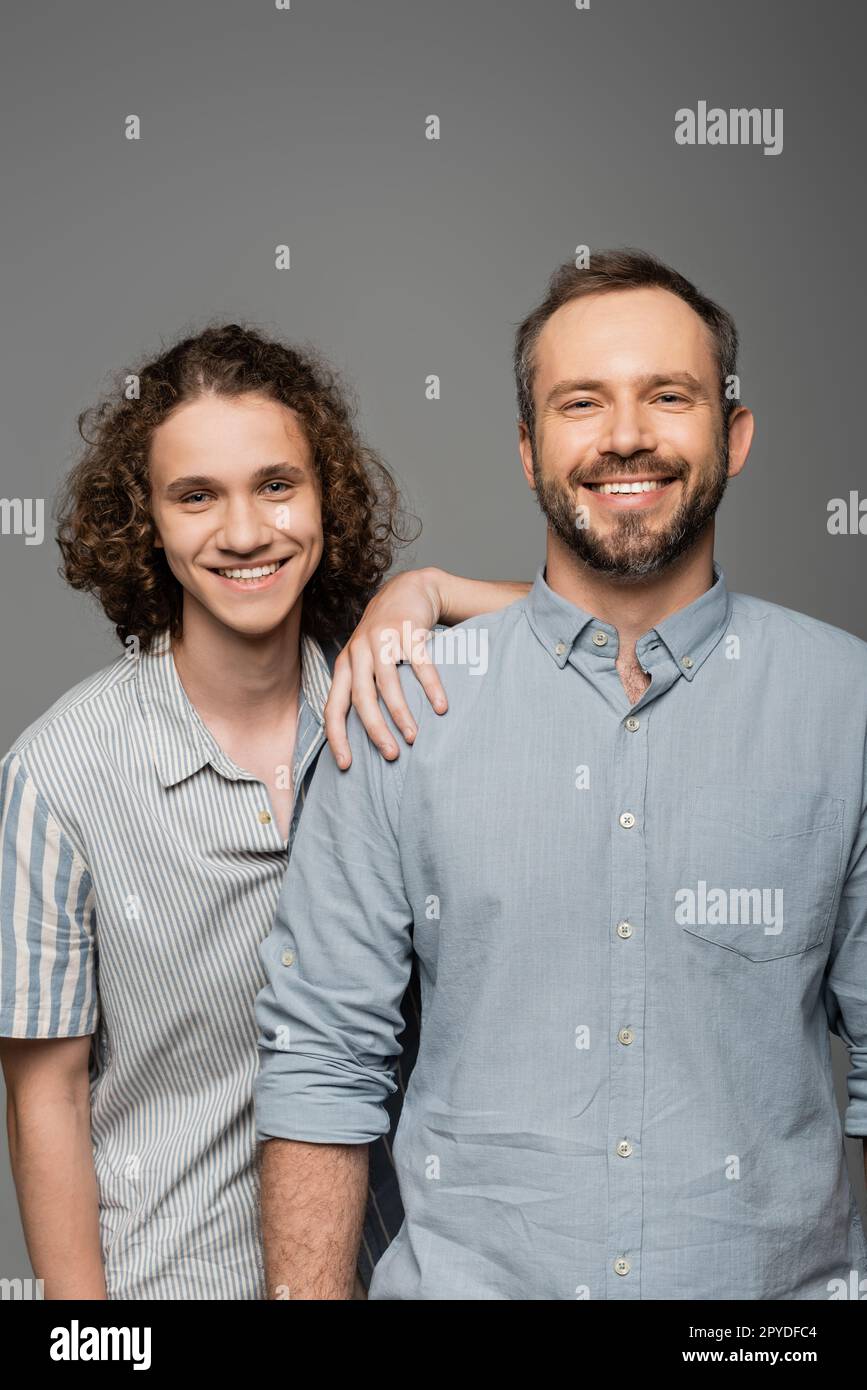 happy father and son in shirts looking at camera and smiling isolated ...