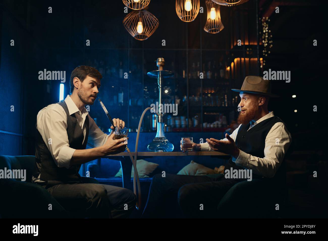 Guys having serious conversation while sitting face to face at hookah ...