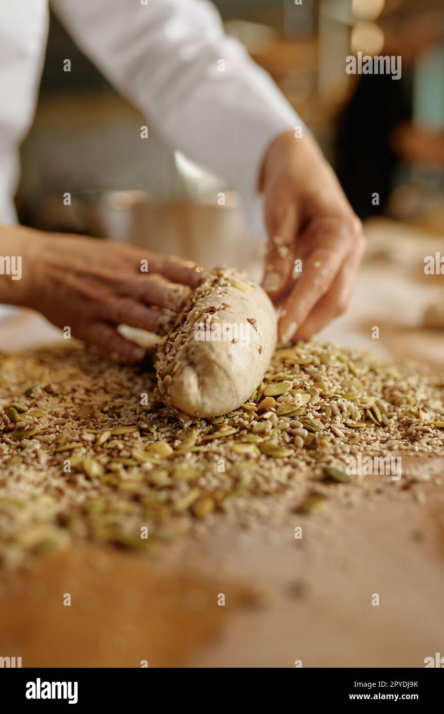 Baker shaping bread bagels with seeds Stock Photo - Alamy