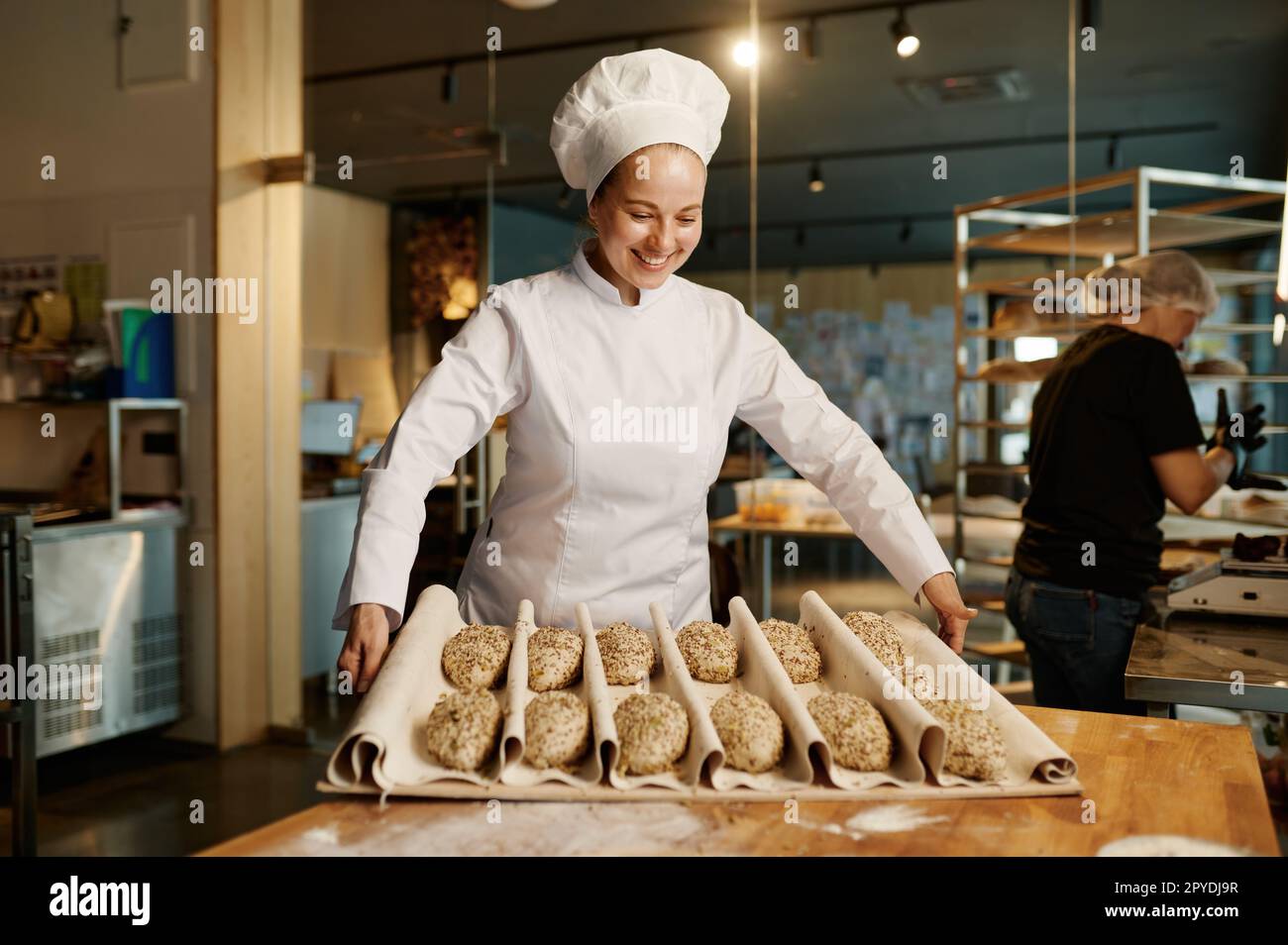 Woman baker preparing sweet buns pastries with sesame seeds Stock Photo ...