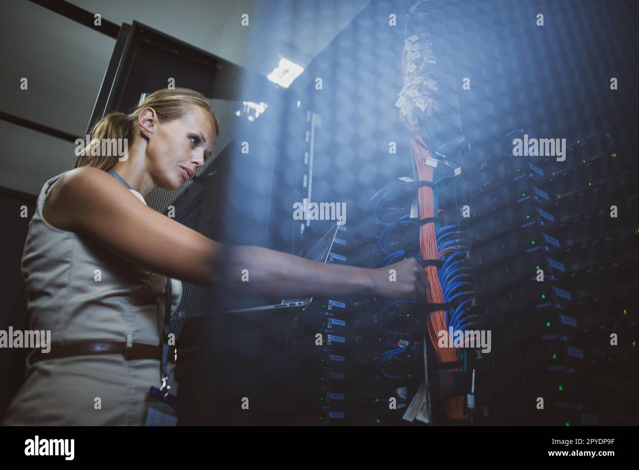 IT engineer standing before working server rack doing routine maintenance check and diagnostics ...