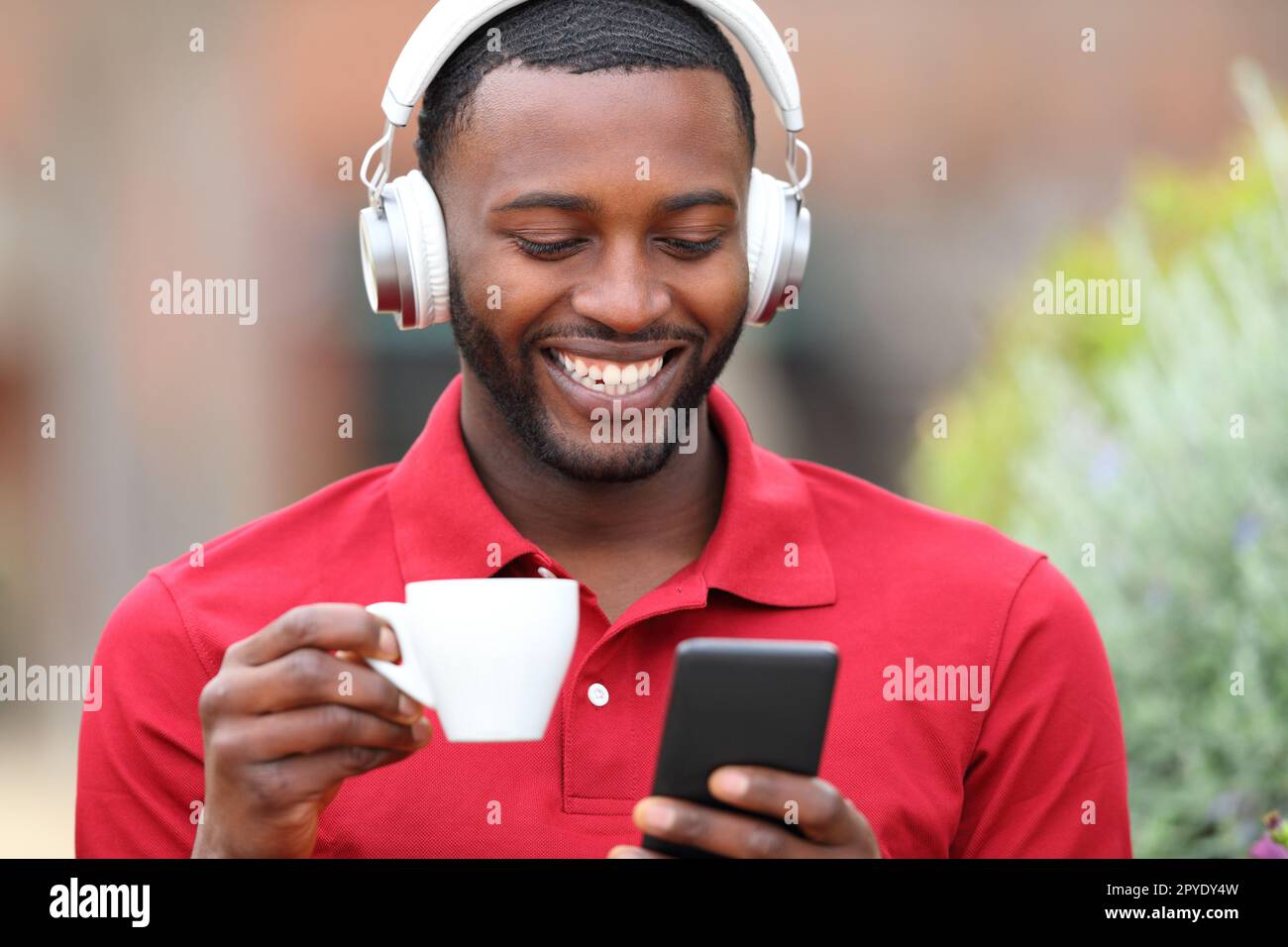 Happy black man listening to music drinking coffee Stock Photo - Alamy