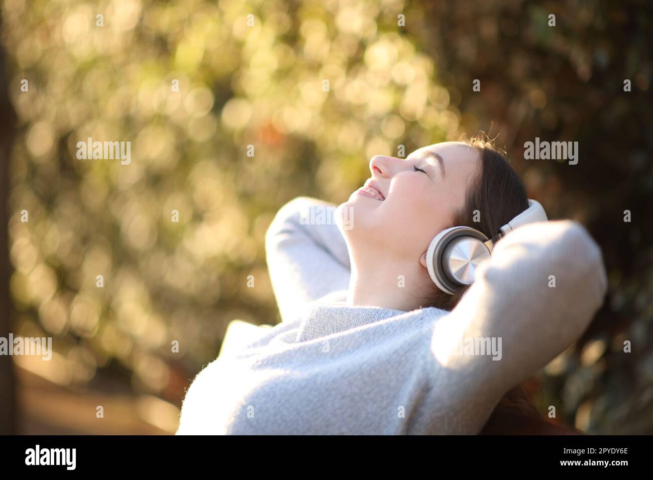 Woman relaxing listening audio with headphone in a bench Stock Photo ...