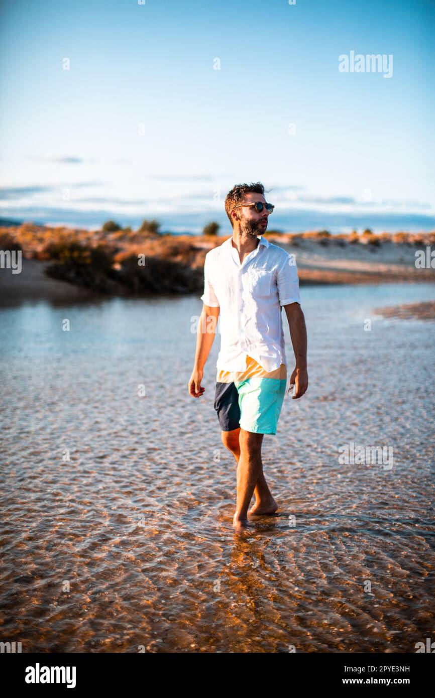 A man is taking a leisurely stroll through a shallow body of water ...