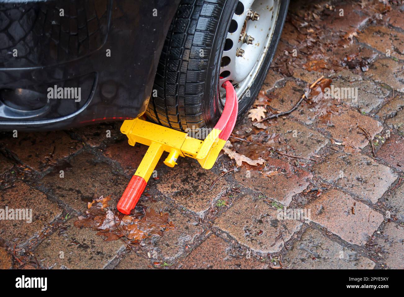 A car is prevented from moving forward by a parking claw, tire claw ...