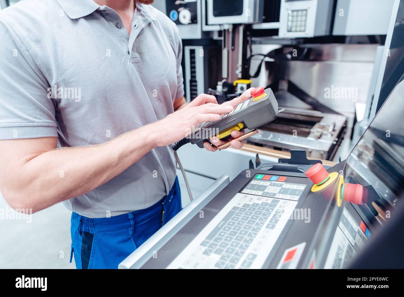 Worker pushing button to operate machine tool in manufacturing line ...