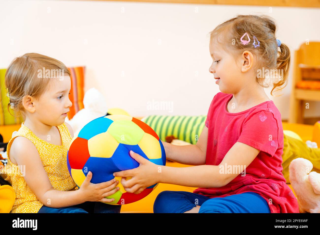 Two girls in play school having fun with a ball Stock Photo - Alamy