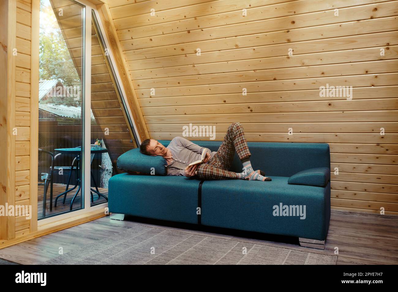 Middle aged man has retired to a country house and is reading a book ...