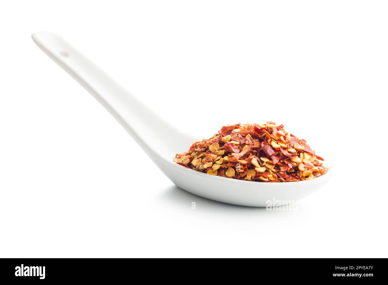 Dry chili pepper flakes in ceramic spoon. Crushed red peppers isolated ...