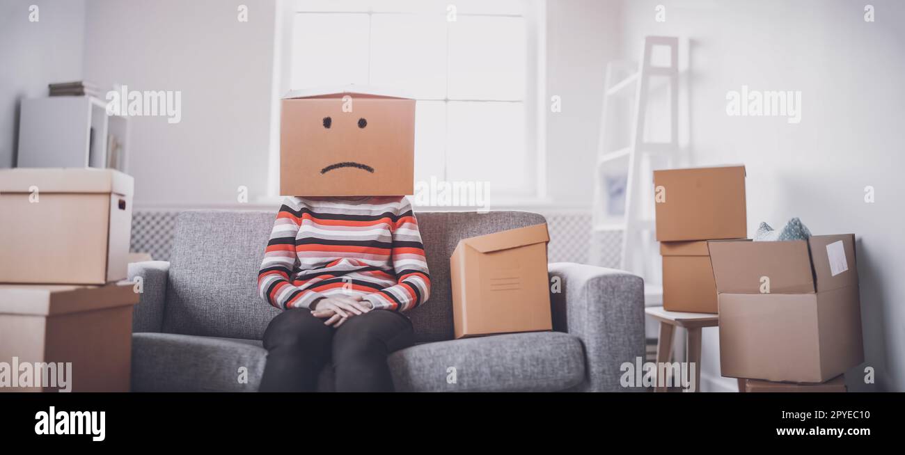 Tired sad woman with cardboard box on her head sitting on the sofa in ...