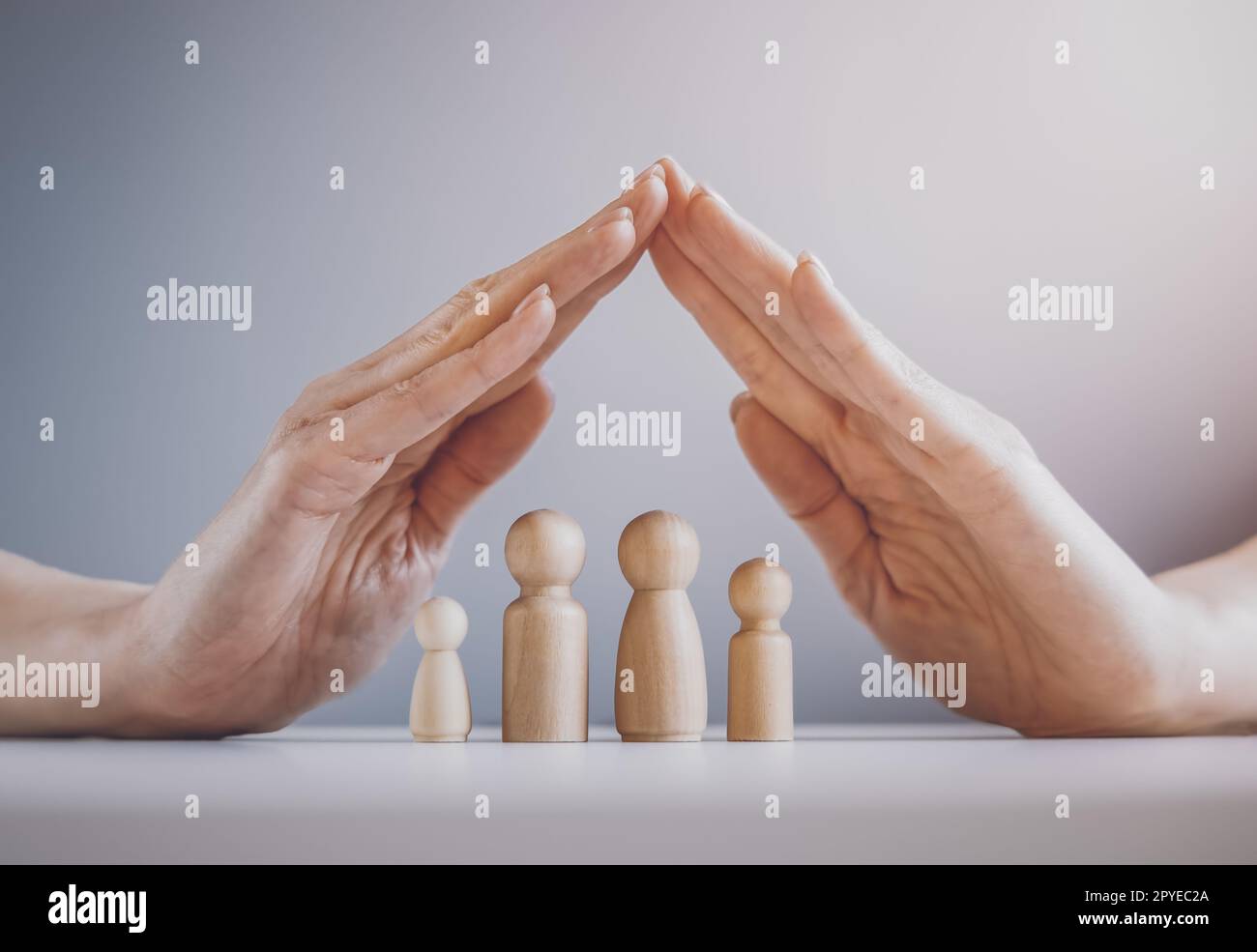 Women's hands over wooden family models on the grey background Stock ...
