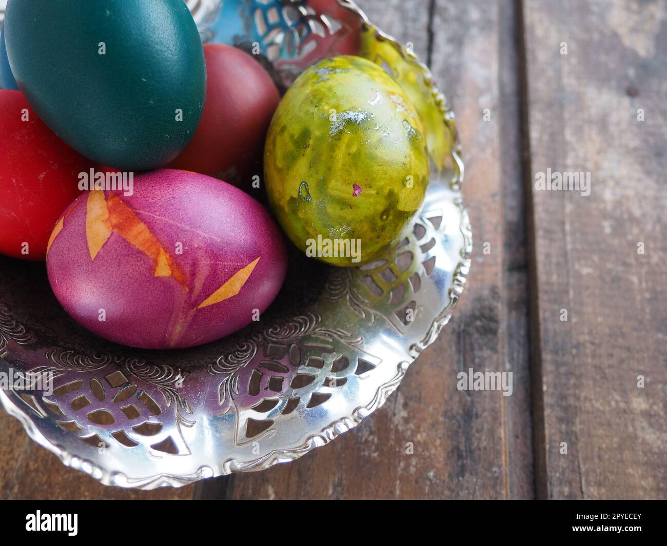 Easter colored eggs in an old metal candy bowl on a wooden table ...
