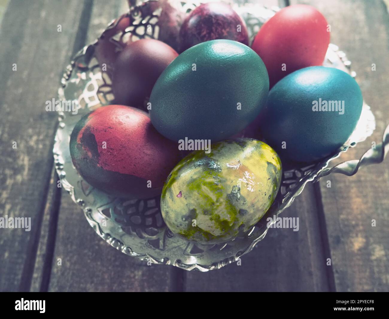 Easter colored eggs in an old metal candy bowl on a wooden table ...