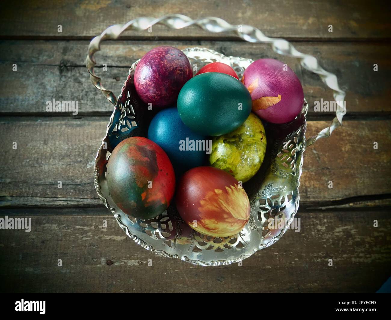 Easter colored eggs in an old metal candy bowl on a wooden table ...