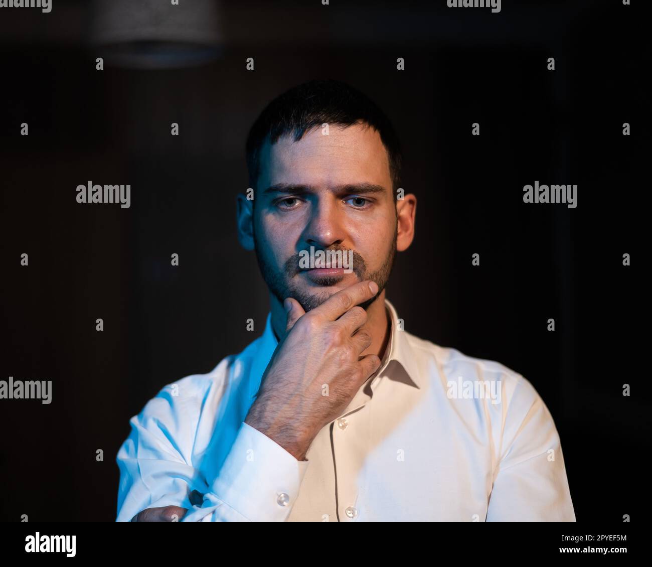A bearded man stands in the dark and looks ahead puzzled Stock Photo ...
