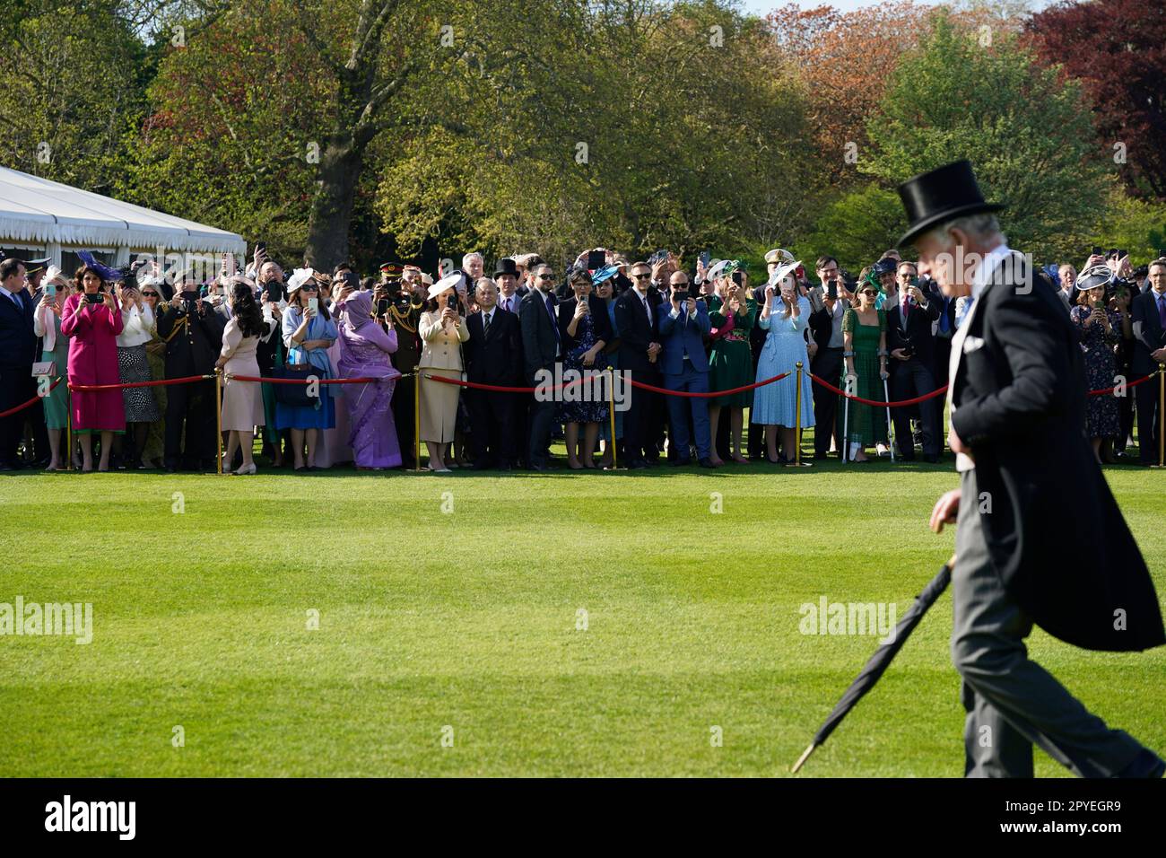 Guests watch as Britain's King Charles III walks, during a Garden Party ...