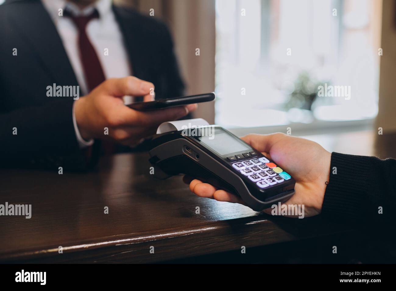 A businessman pays a bill for a hotel room through a smartphone using ...