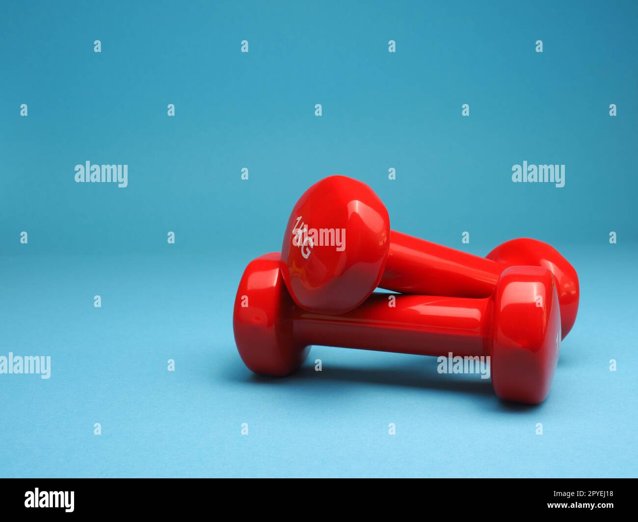 Red dumbbells on a blue background Stock Photo - Alamy