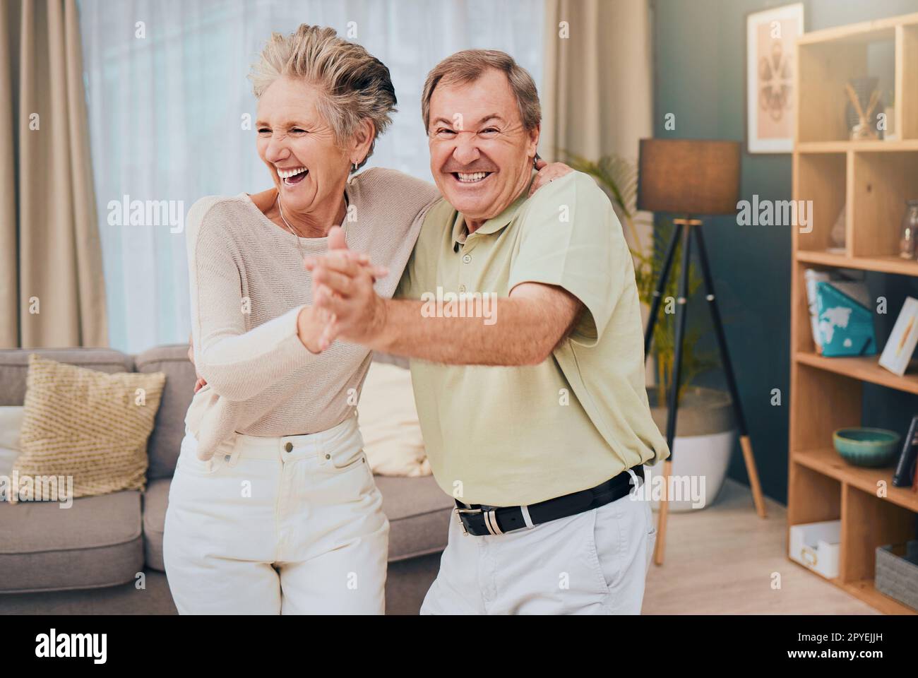 Happy, dance and senior couple in a living room, smile and fun while being silly in their home ...