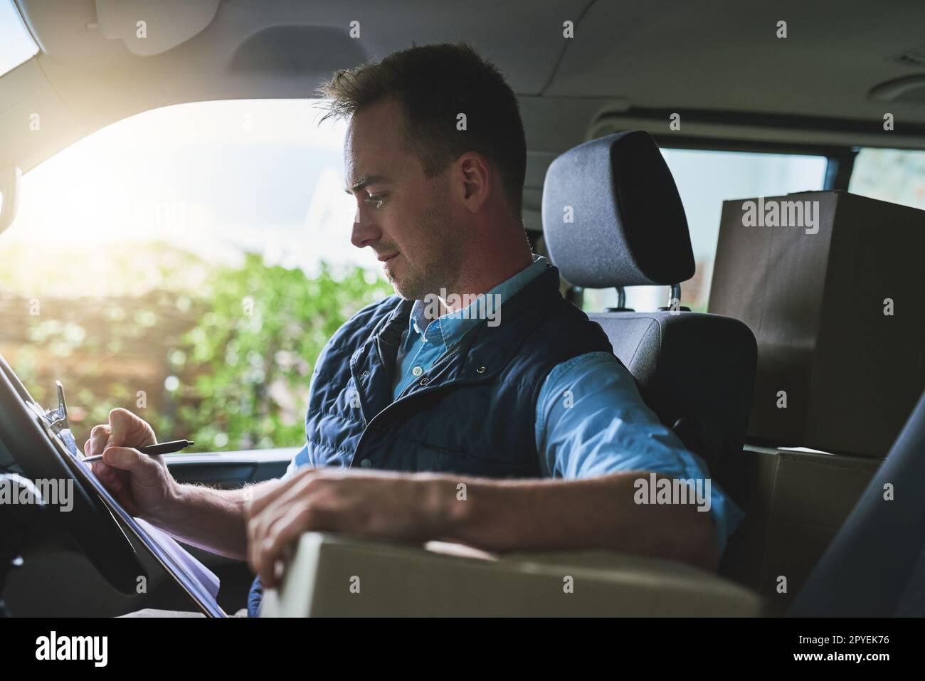 Organizing his next delivery stops. a courier writing on a clipboard ...