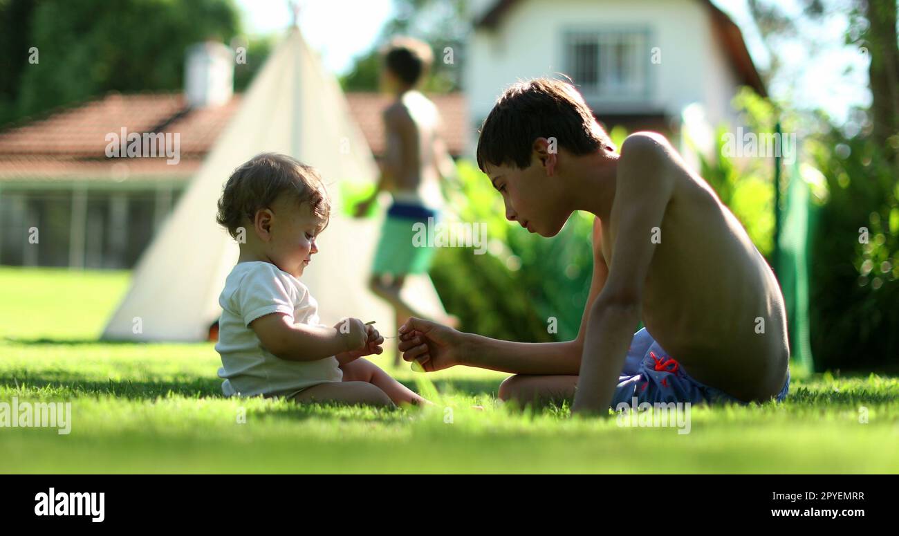 Two brothers interacting together outside in home backyard. Older ...