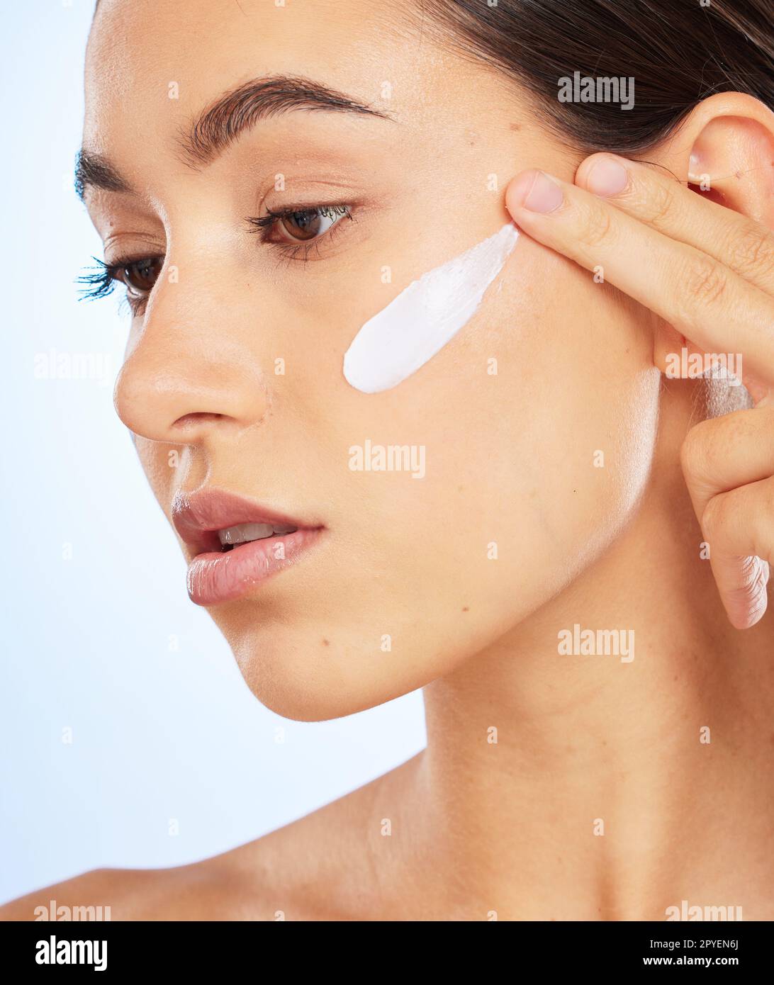 Face, beauty skincare and woman with cream in studio isolated on a blue ...