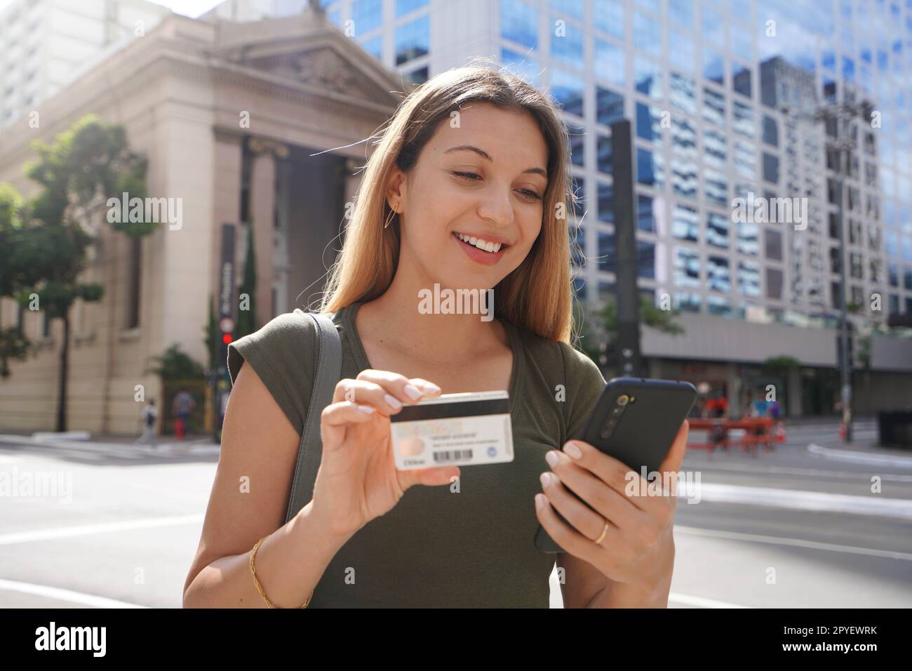 Portrait of young business woman watching her phone holding credit card ...