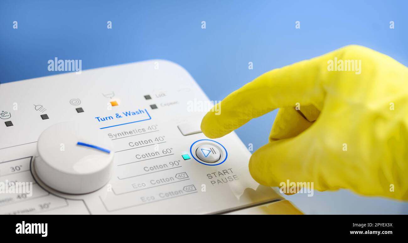 Finger in yellow glove about to press button switch on atomatic washing ...