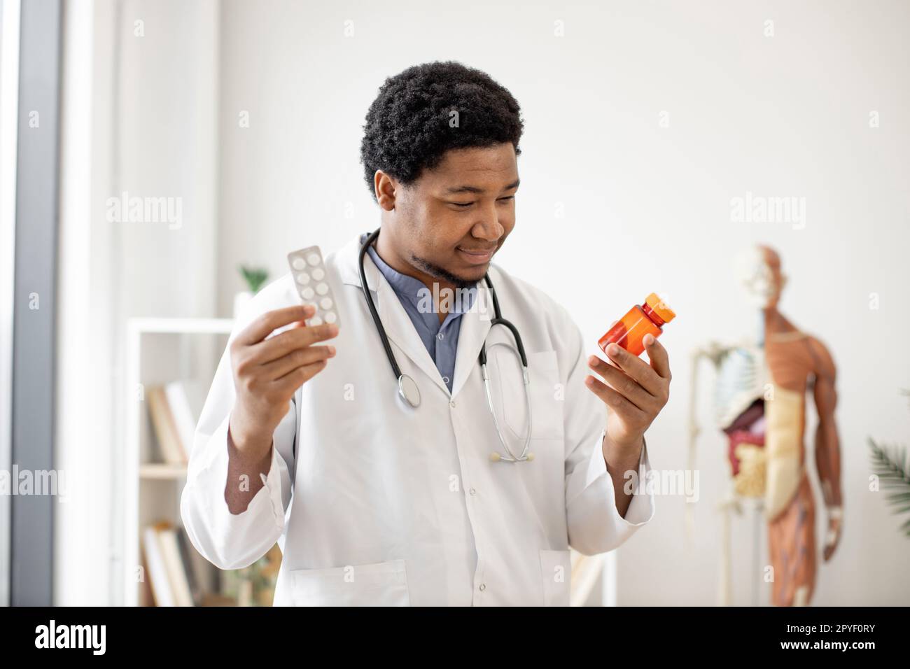 Friendly multiethnic man in lab coat scanning pill bottle while ...