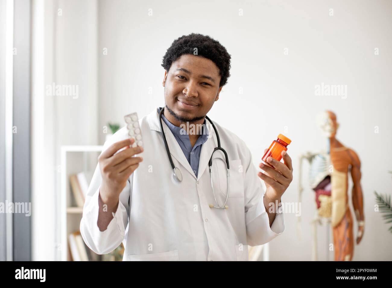 Friendly multiethnic man in lab coat scanning pill bottle while ...
