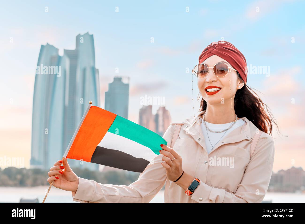 Indian girl with UAE flag against scenic skyscrapers in Abu Dhabi ...