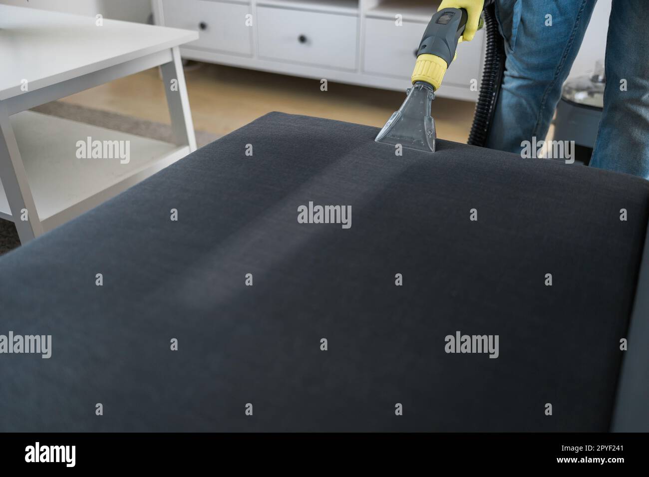 Man in protective rubber glove cleaning sofa with professionally ...