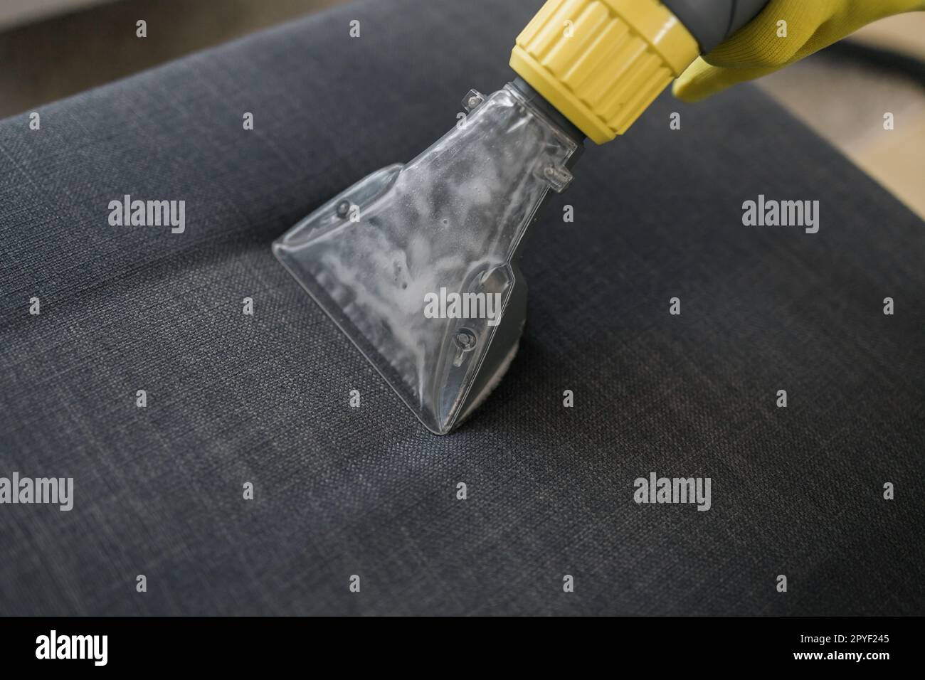 Man holding modern washing vacuum cleaner and cleaning dirty sofa with ...