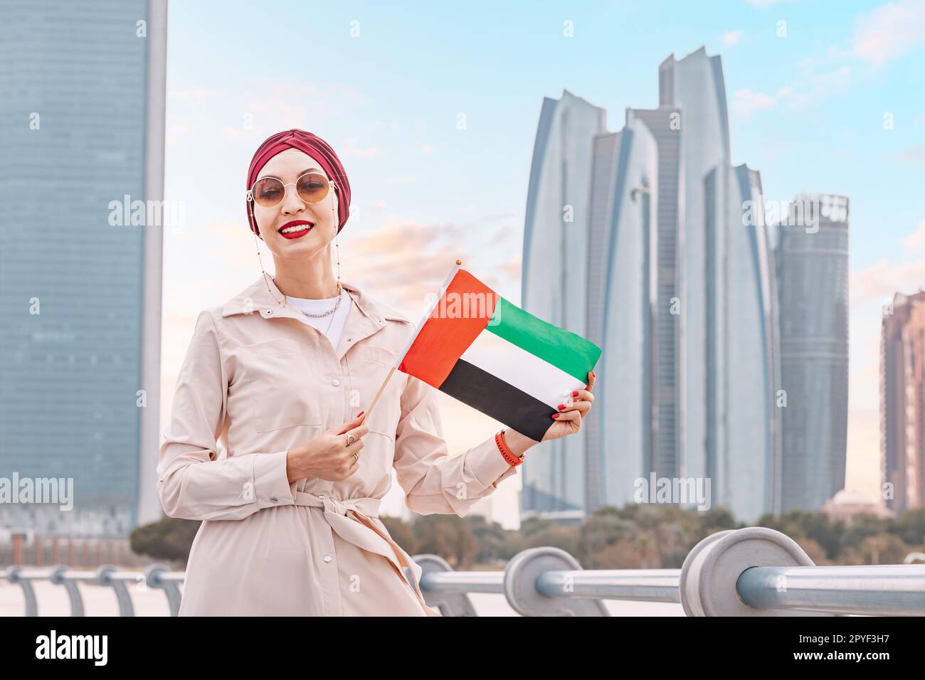 Indian girl with UAE flag against scenic skyscrapers in Abu Dhabi ...