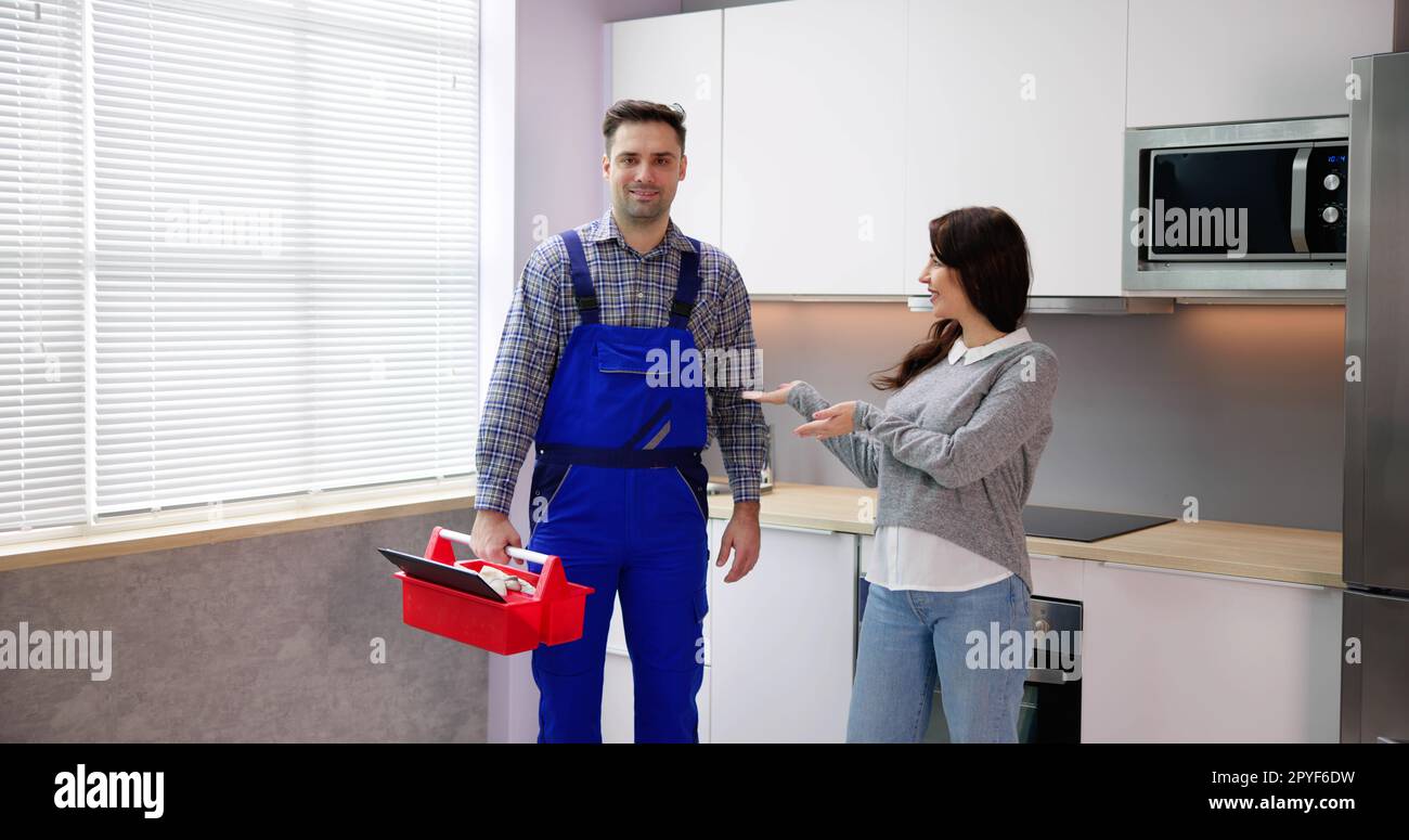 Happy Woman Presenting Male Repairman Stock Photo - Alamy