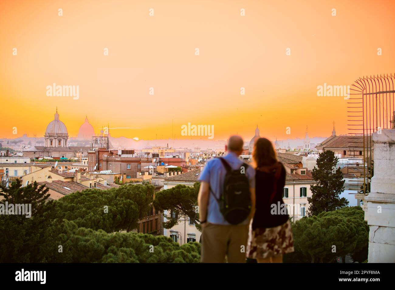 Two tourists watch the sunset in Rome and the Roman landscape.View of ...