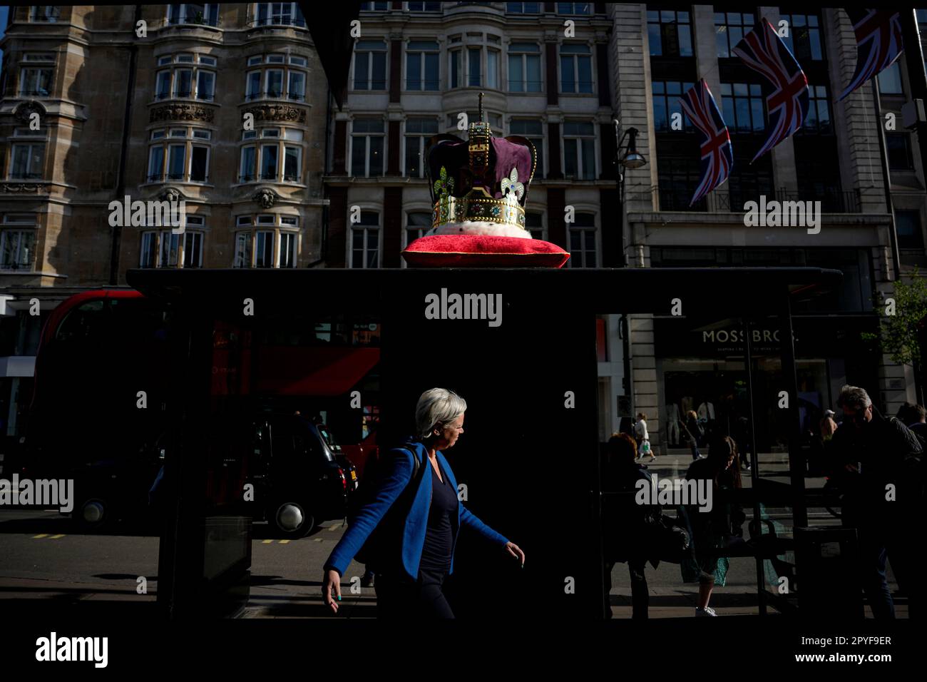 A woman walks under a giant crown decorating a bus station ahead of the ...