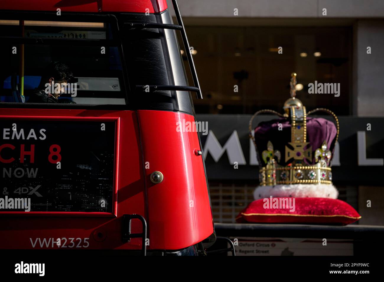 A man sits on a bus near a giant crown decorating a bus station ahead ...