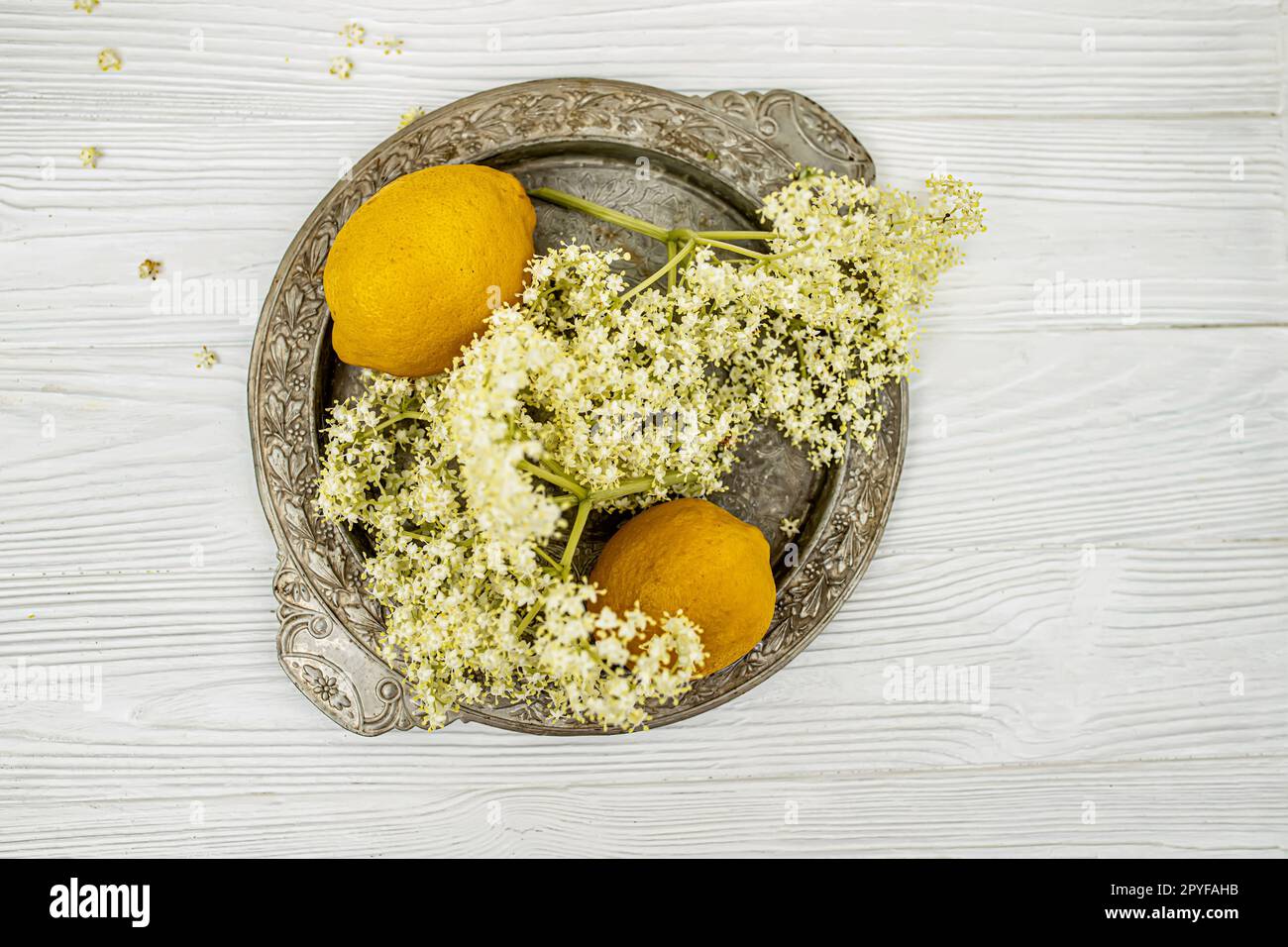 A transparent glass with a slice of lemon and a bouquet of elderberry ...