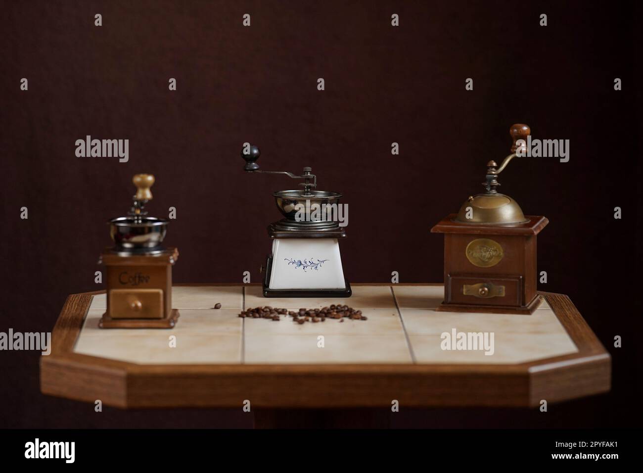 Three retro coffee grinders stand on the table on a cinnamon background ...