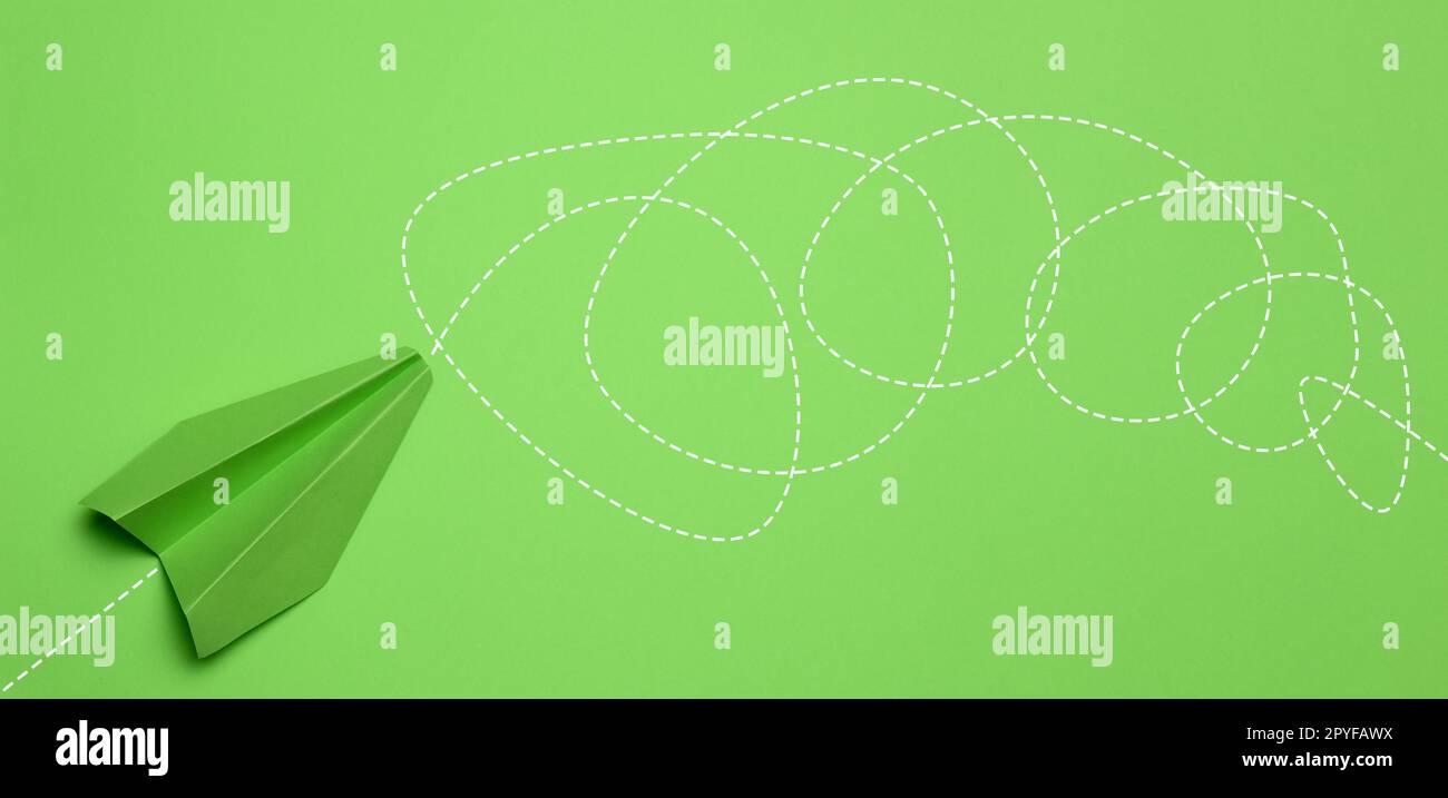 A green paper airplane on a green background with a long and convoluted ...