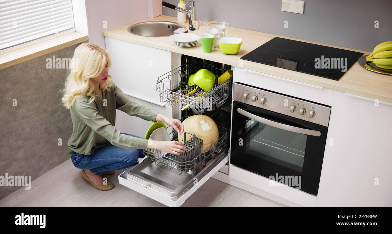 Happy Young Woman Arranging Plates In Dishwasher Stock Photo - Alamy