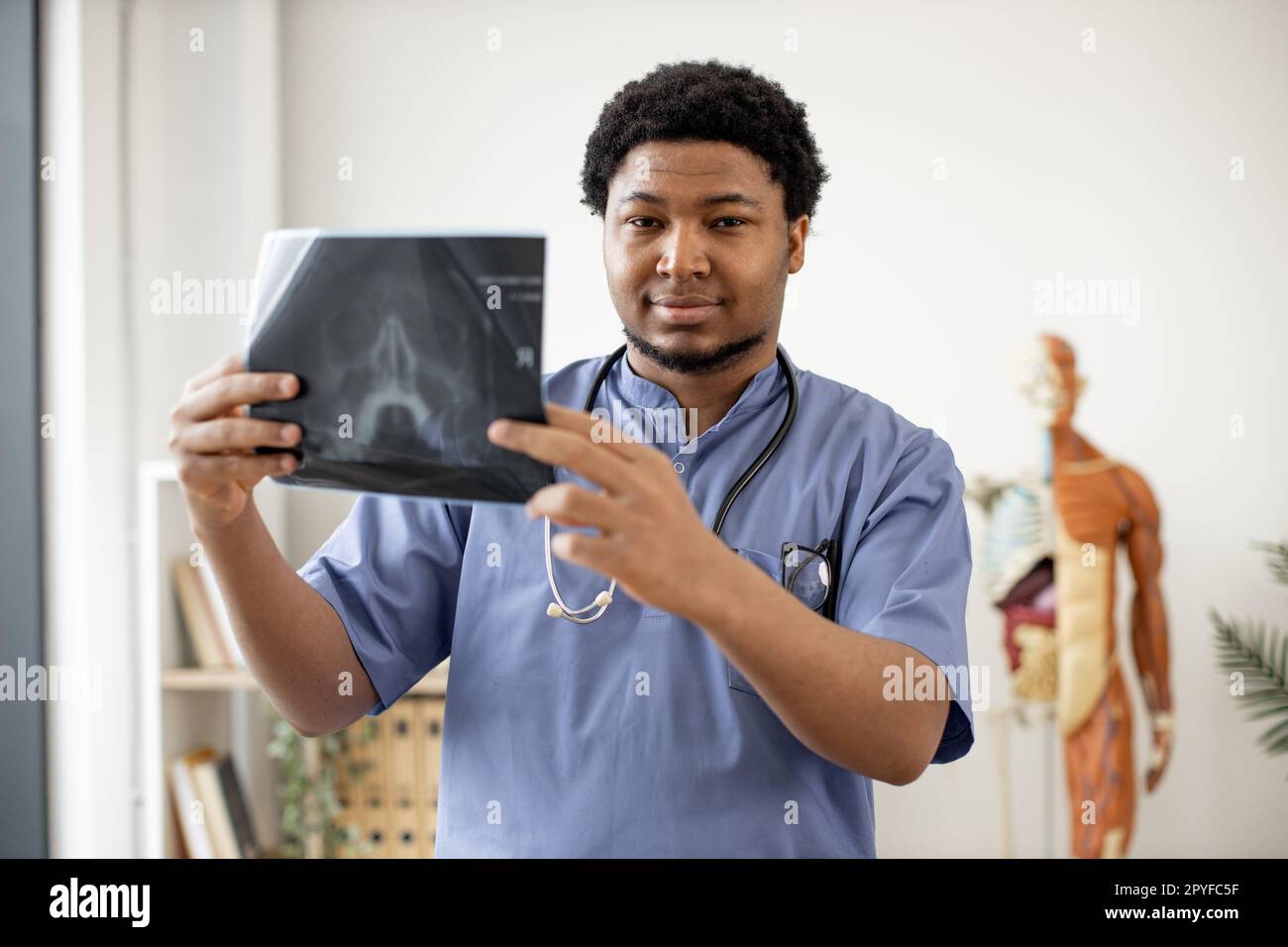 Mindful multiethnic male in scrubs wearing stethoscope and folded ...