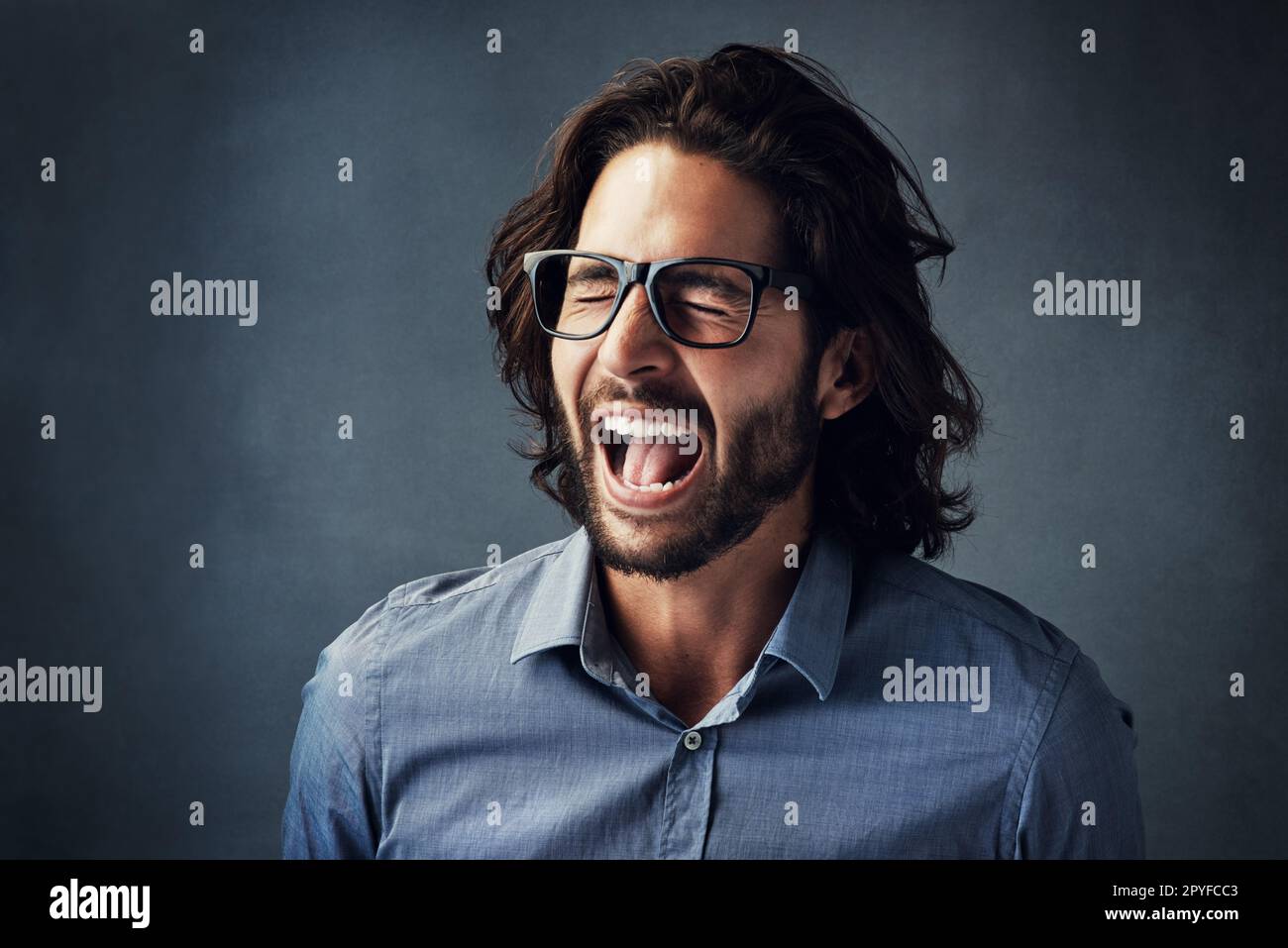 Can you hear me now. Studio shot of a handsome young man shouting while ...
