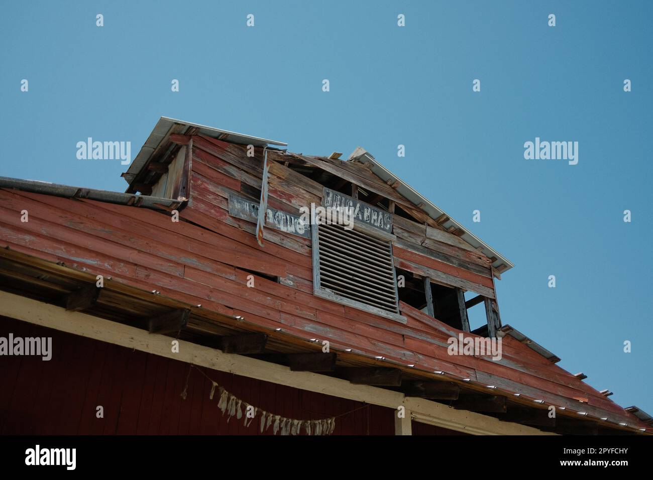 An aged red wooden building with an array of windows and boarded-up ...