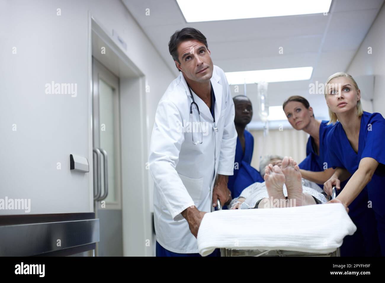 Getting ready for surgery. A team of doctors pushing a patient down the ...