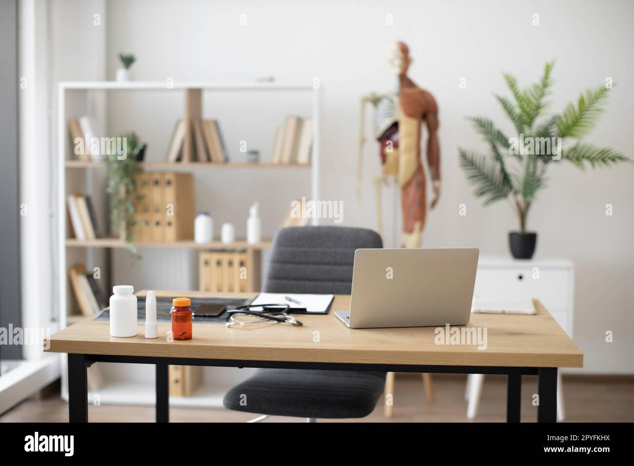 Focus on writing desk with modern laptop, stethoscope, and medicine ...