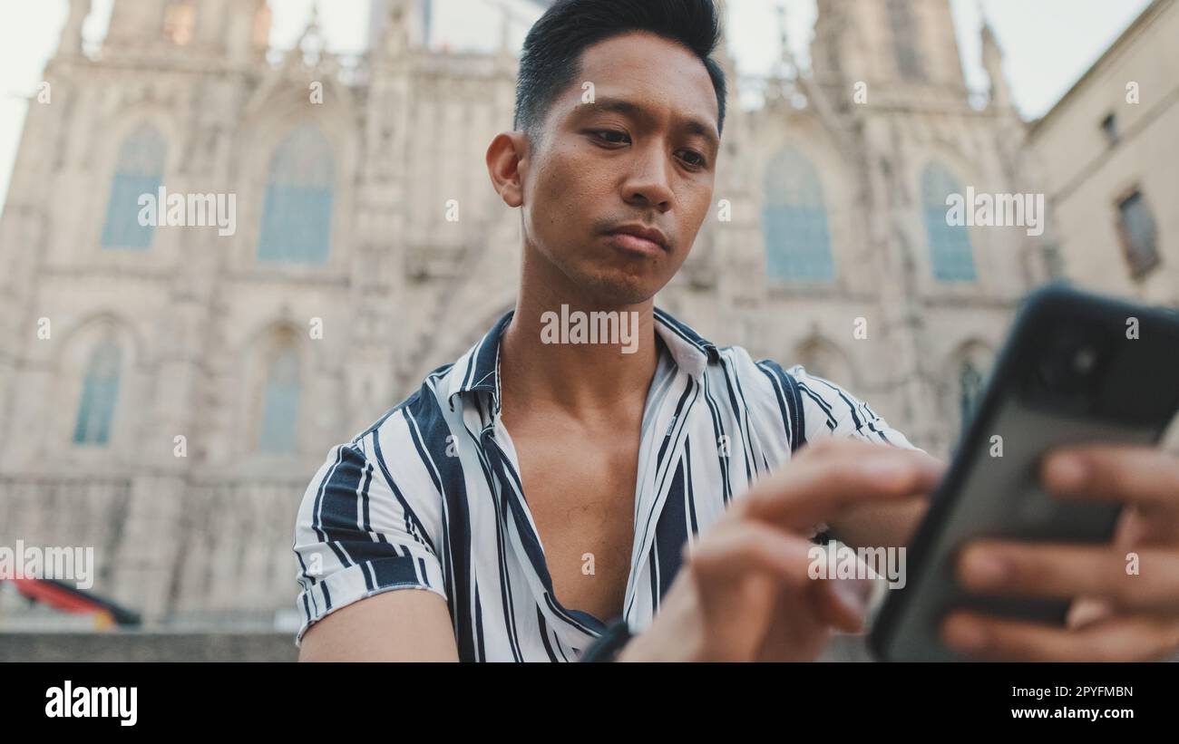 Young man tourist on steps uses mobile phone while sitting on landmarks ...